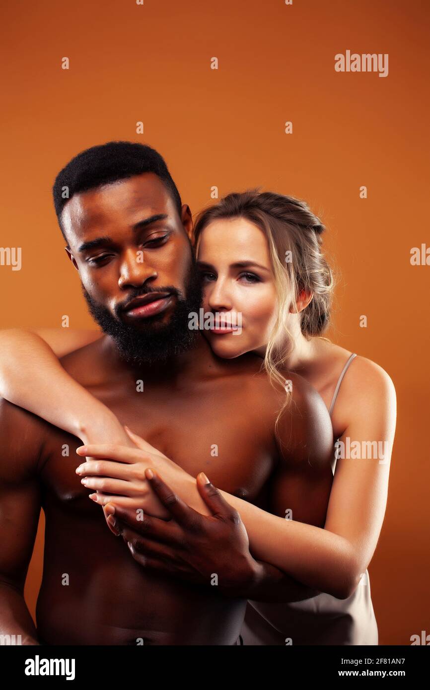 Young pretty couple diverse races together posing sensitive on brown background, lifestyle ...