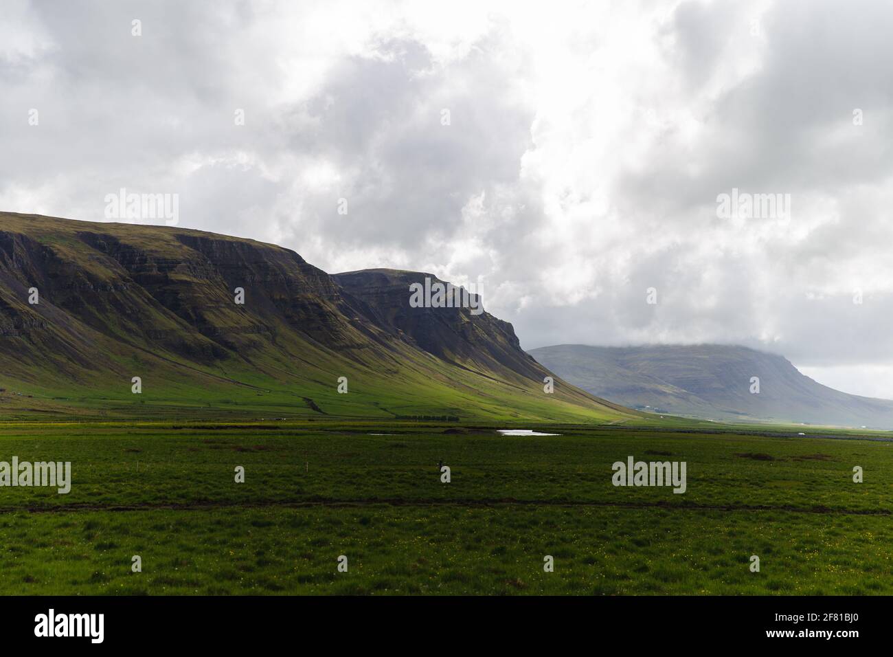 view of a valley with a cliff on the left and black sand on the ground ...