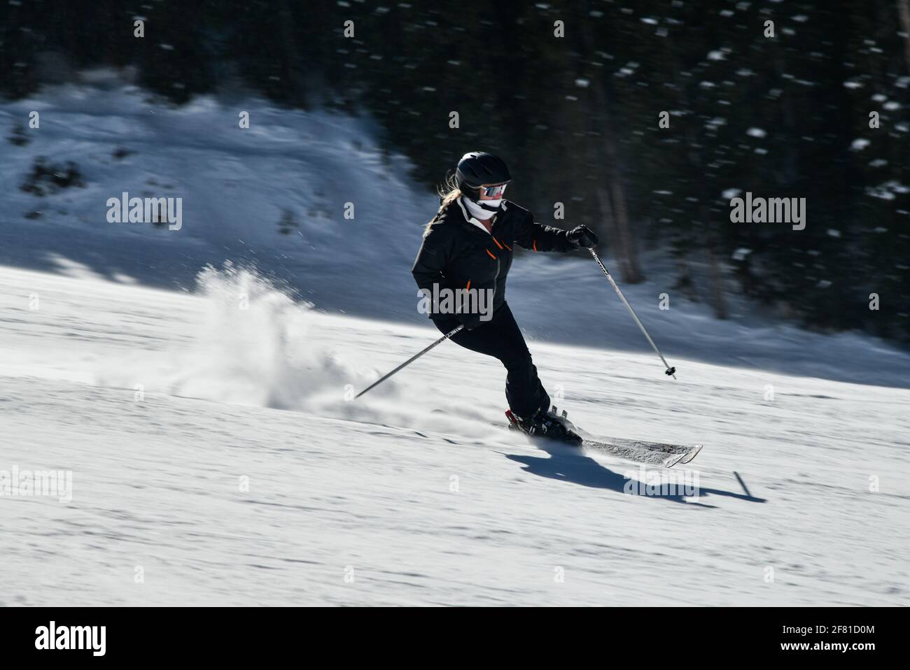 Female Skier going down the slopes on hi-speed at sunny day with fresh ...