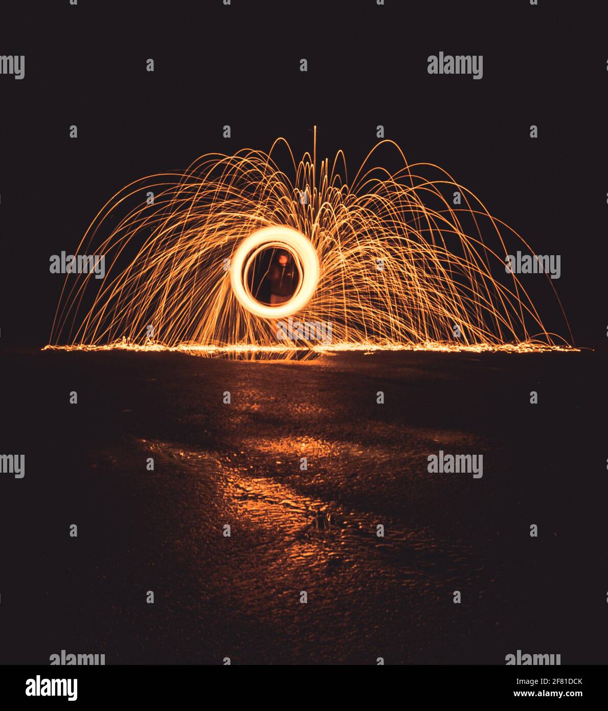 Man creating rotating and swirling sparks in a dark place and on the ...