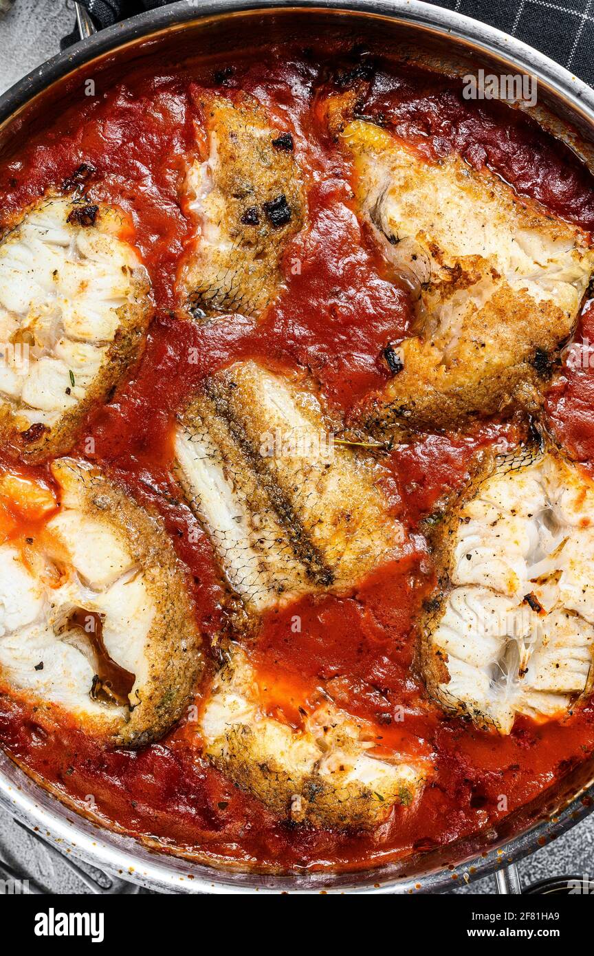 Baked grenadier macrurus white fish with tomato in a pan. White Wooden ...