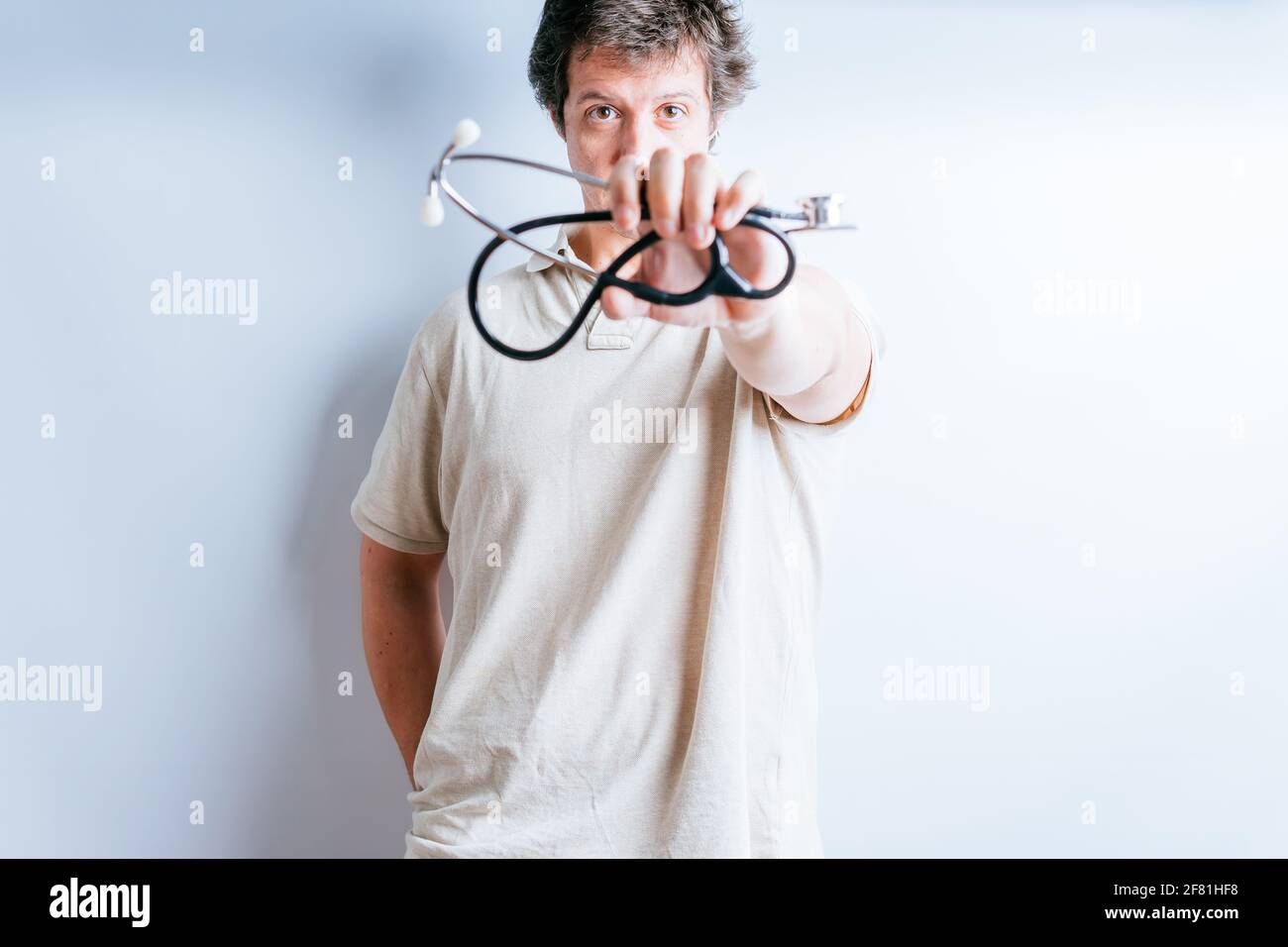 Attractive young man showing a stethoscope in front on white background ...