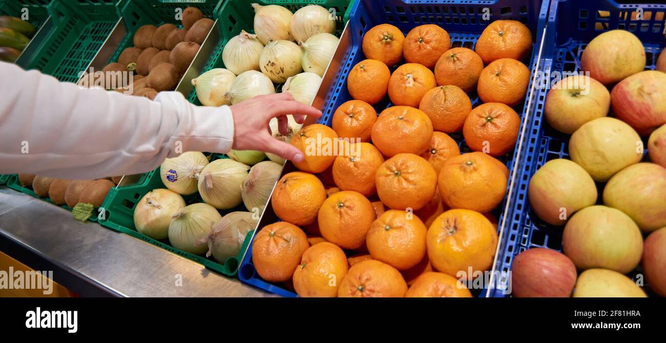 A hand grabbing an orange at a fruits and vegetable market Stock Photo ...