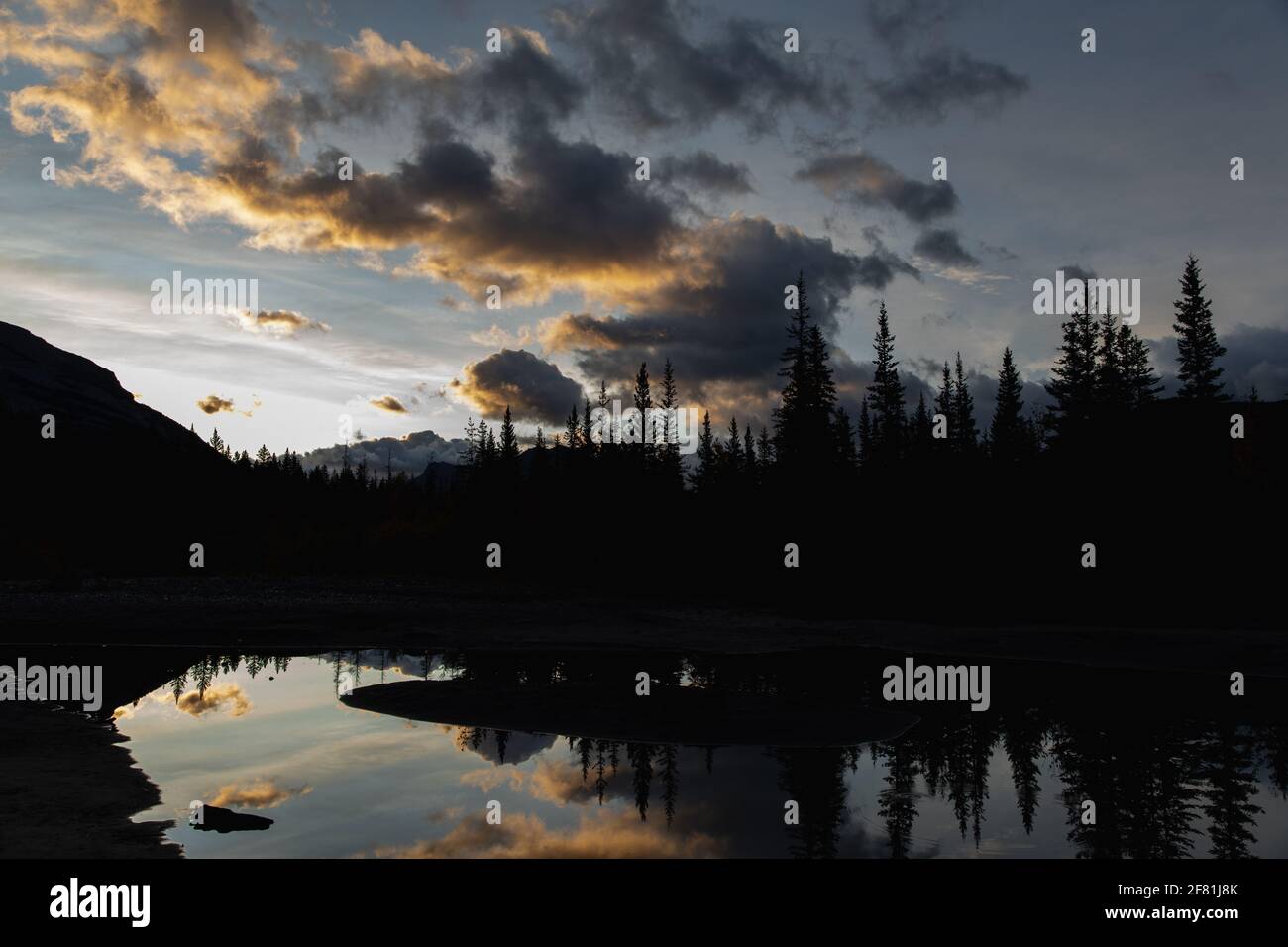 dark and promising morning in the mountains with a lake reflecting the ...