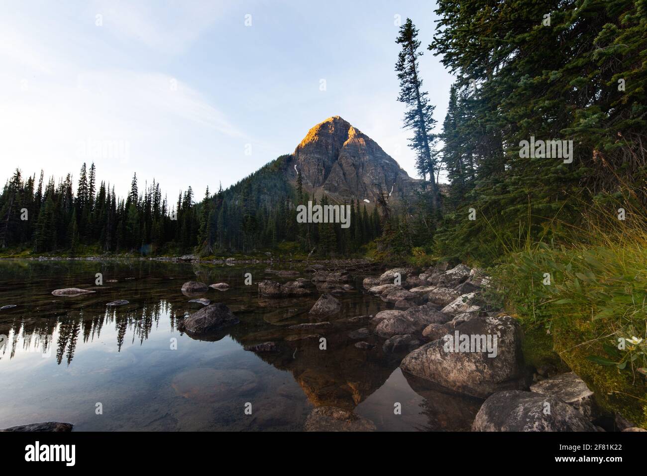 tall peak behind a lake with the sun rays hitting the top of the ...