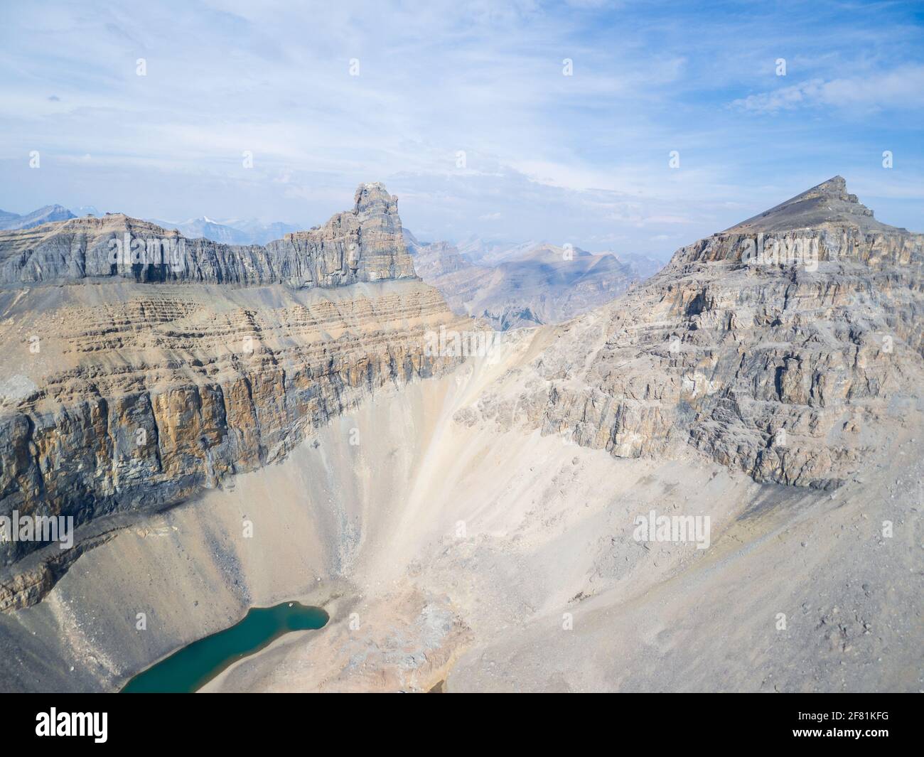 Tall sandy mountains in summer with a tiny turquoise lake with blue sky ...