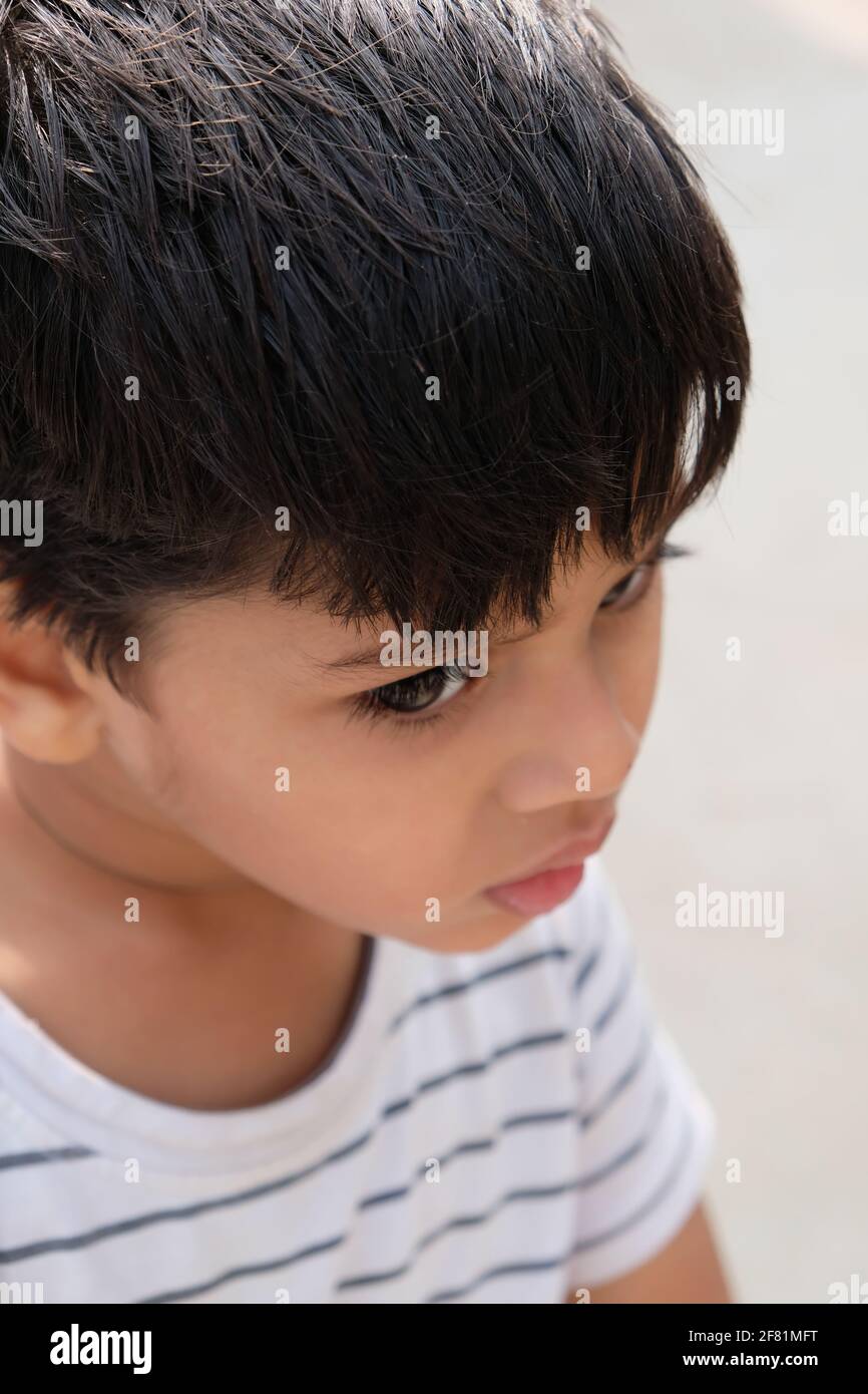 A shallow focus of an Indian boy looking at something with a curious ...