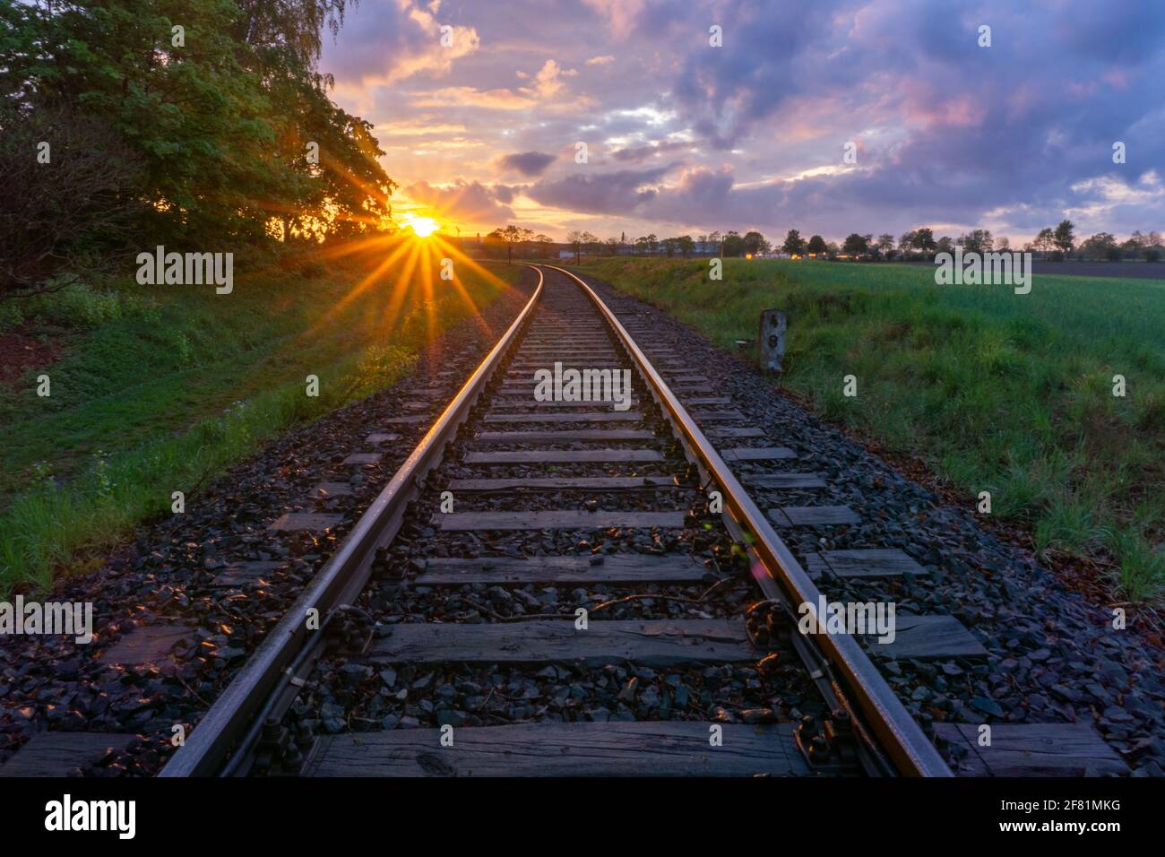 The rails of a train in a field at sunset Stock Photo - Alamy