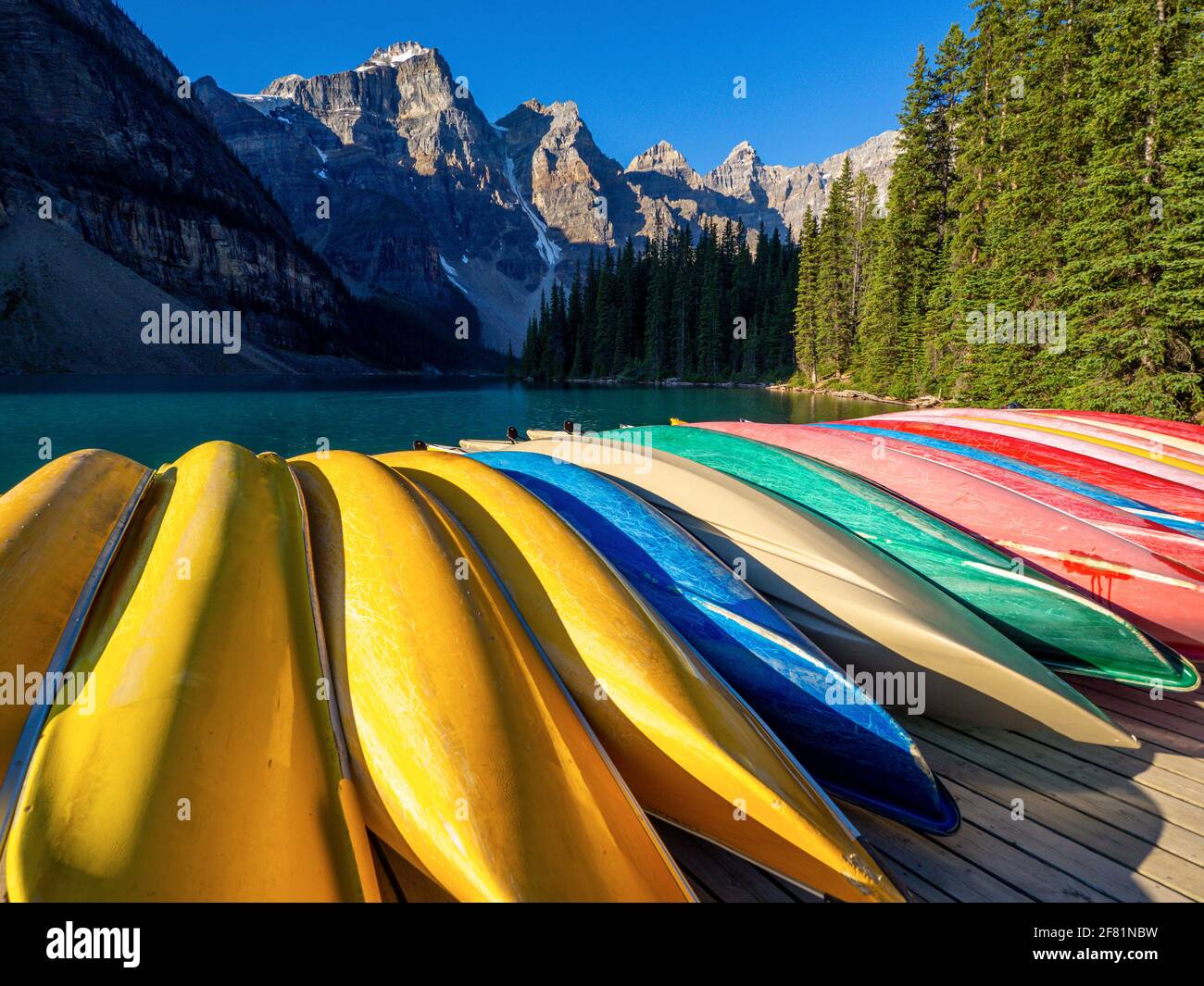 Boats turned over on the dock next to a turquoise lake in summer with ...