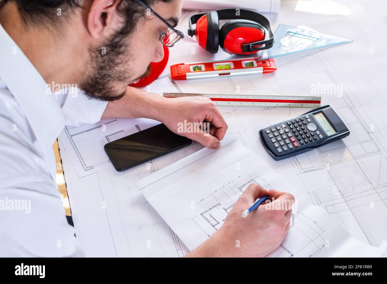 A side view of an Israeli architect-engineer working on a blueprint ...