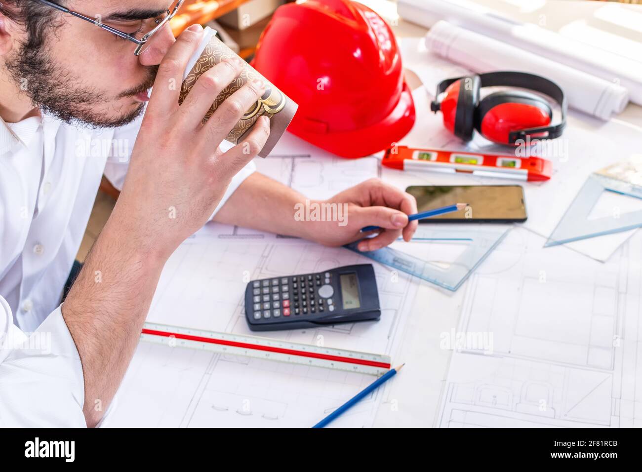 A young Israeli architect-engineer drinking coffee while working Stock ...