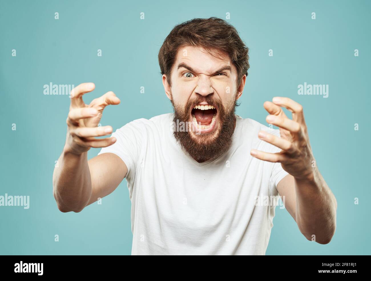 Aggressive man on blue background shows forefinger stress irritability ...
