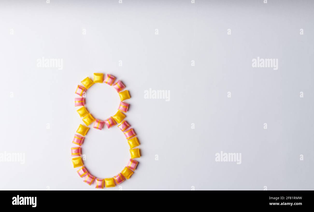 number eight made from red-yellow square candies on white background ...