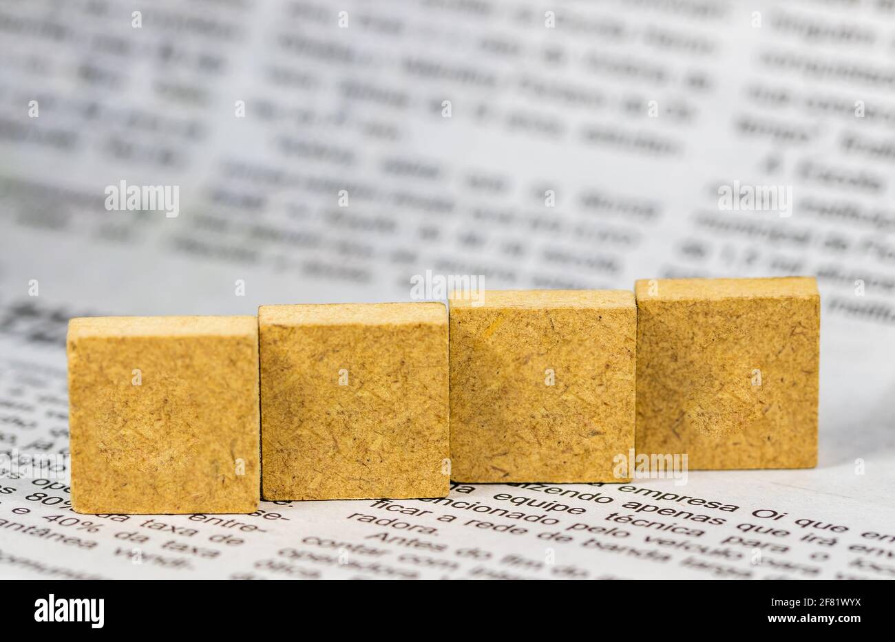 Four blank wooden cube blocks on a newspaper Stock Photo - Alamy