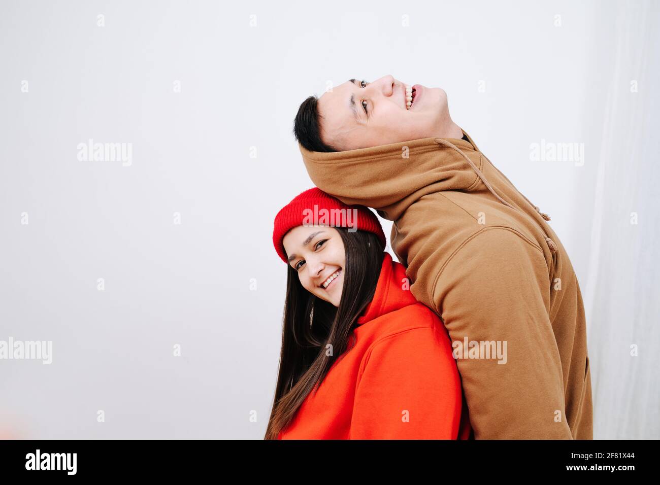 Lovely happy young couple standing back to back, leaning on each other ...