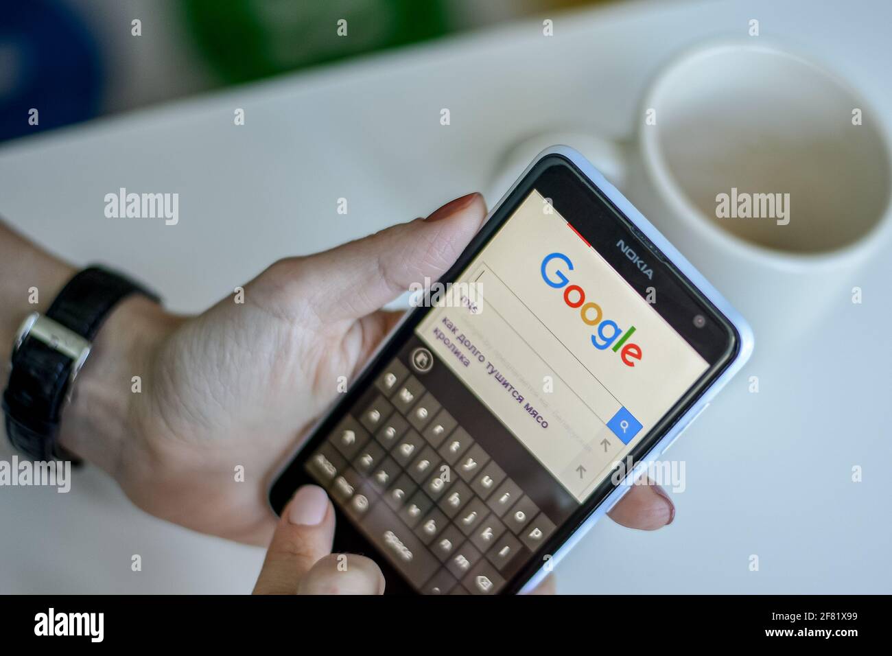 A man uses a mobile device for google search. Mobile phone in the man's ...