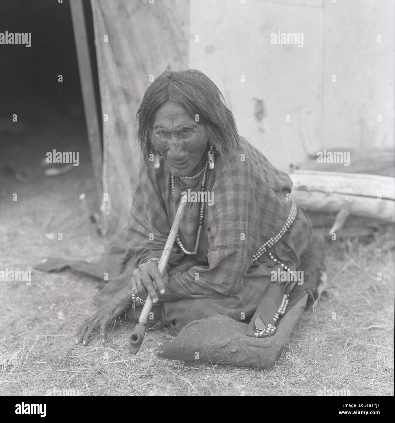 Early photograph of Beaver woman of the Siksika Nation smoking a pipe ...