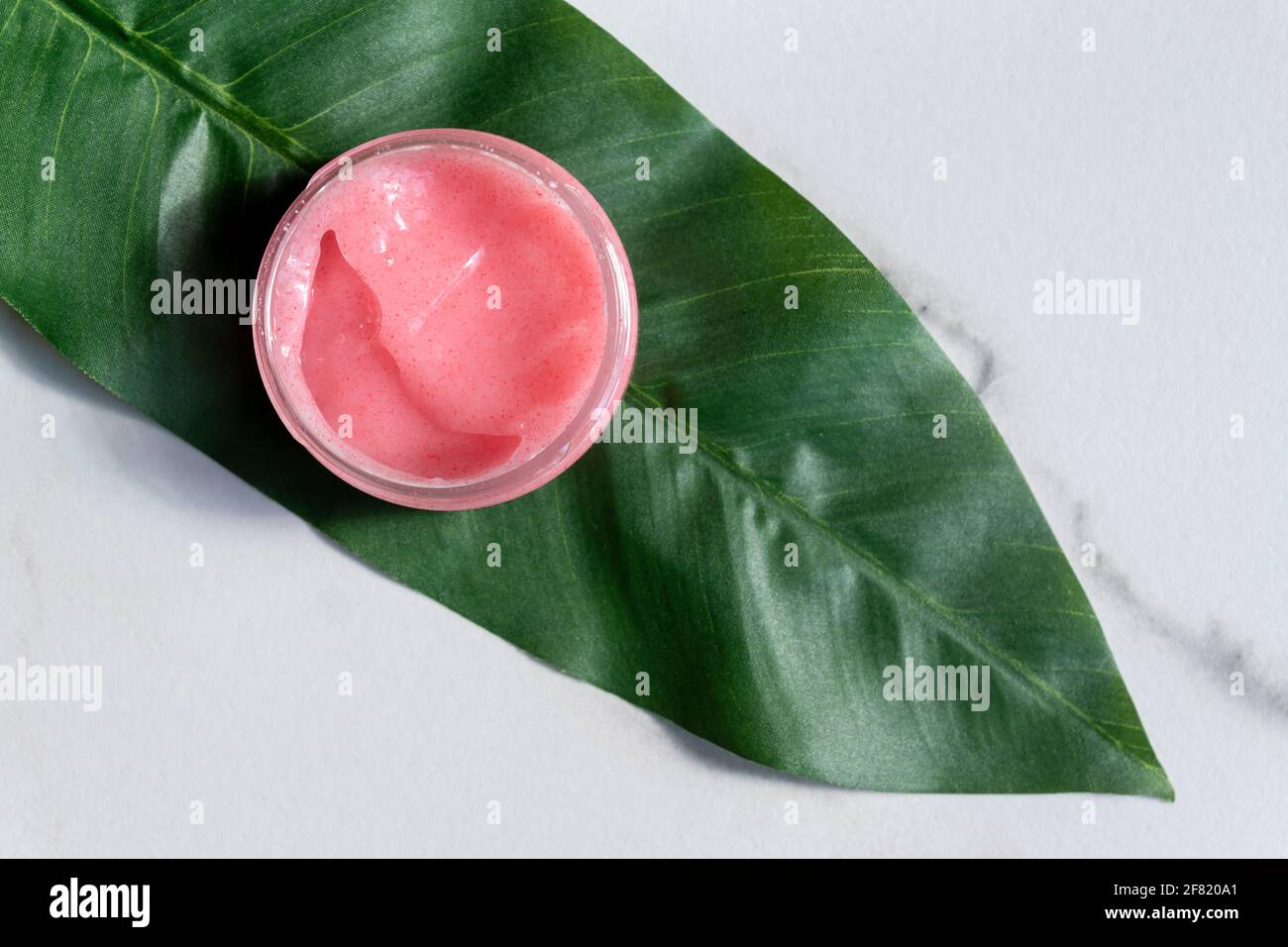 Pink body scrub on tropical leaf on marble background. Wellness and spa ...
