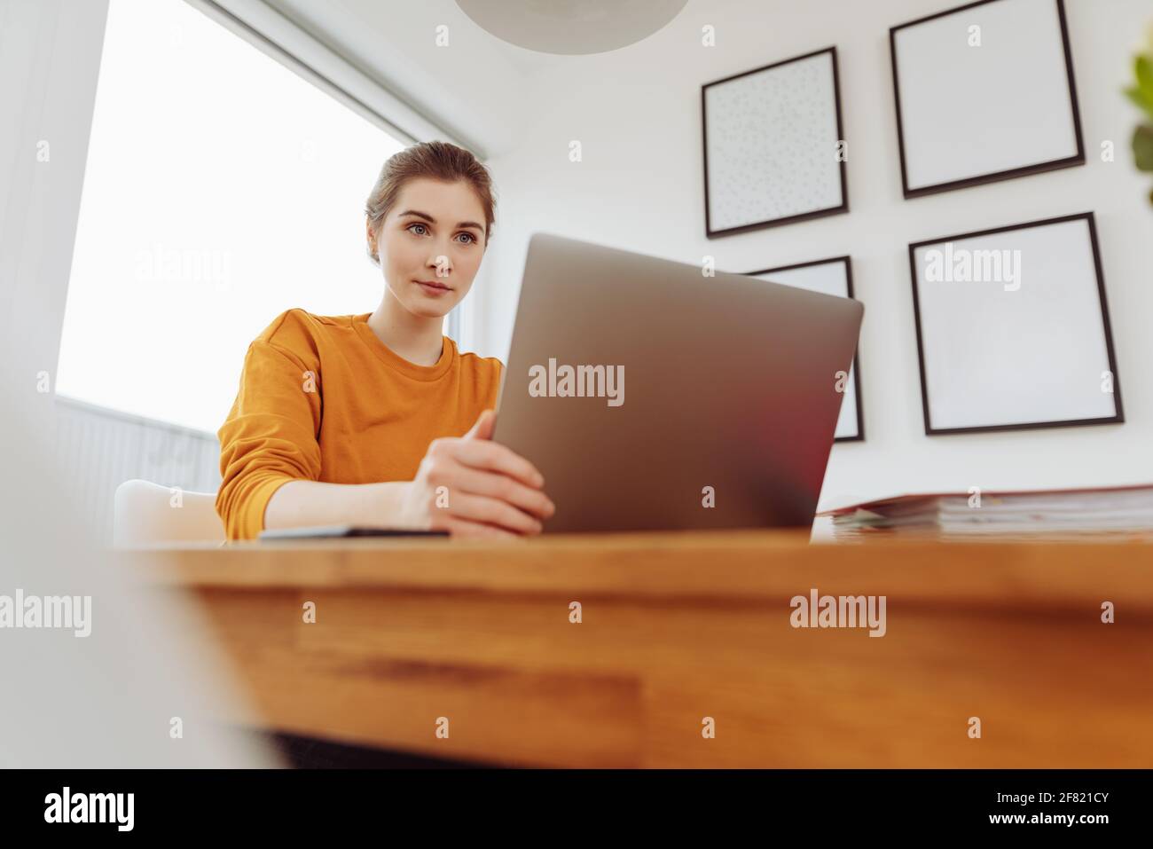 Low angle view of a serious young woman working at a laptop computer ...