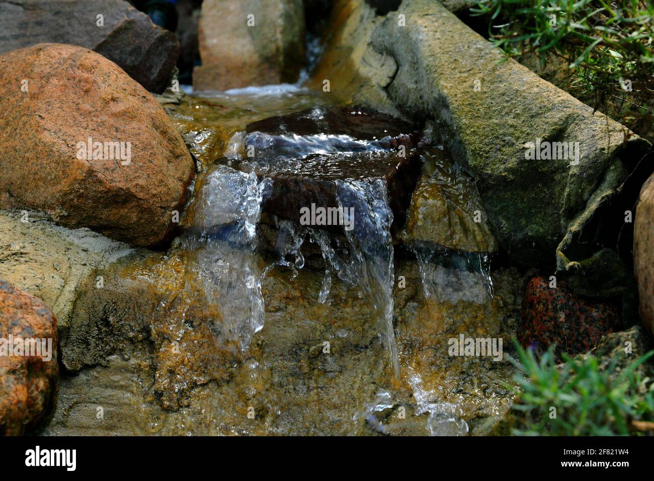 Water cascade built of natural stones and rocks in the backyard garden ...