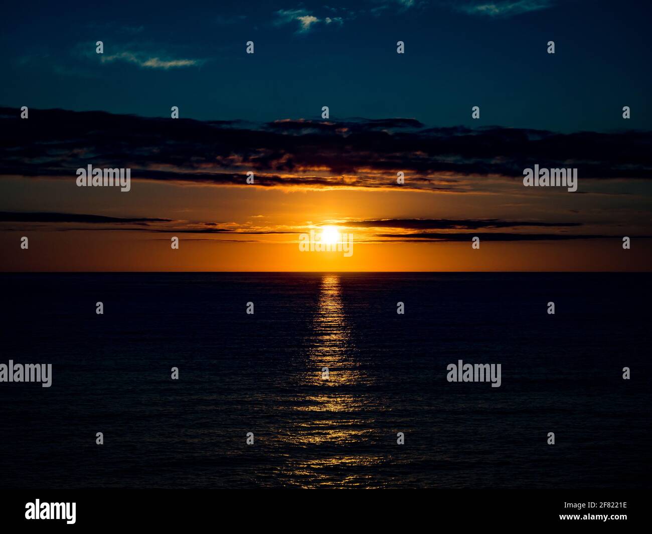 A beautiful golden sunset over the ocean horizon on a warm summers ...