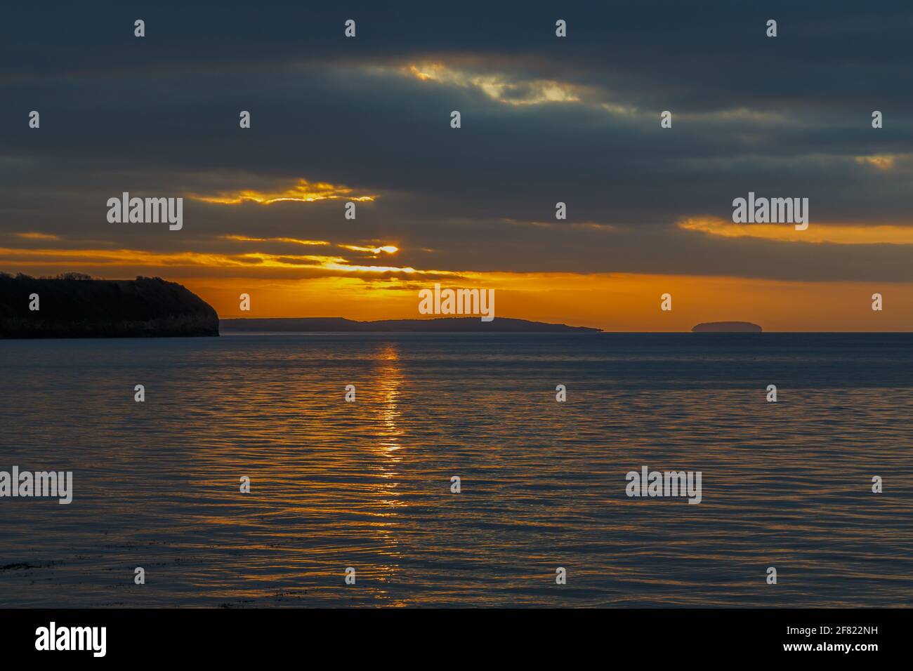 The sun setting over the horizon Stock Photo - Alamy