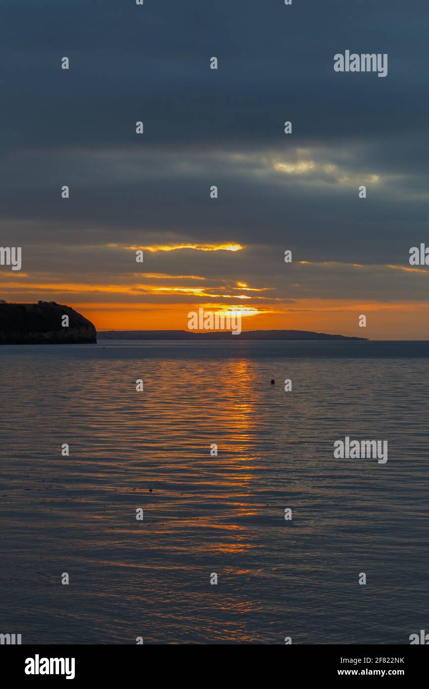 The sun setting over the horizon Stock Photo - Alamy