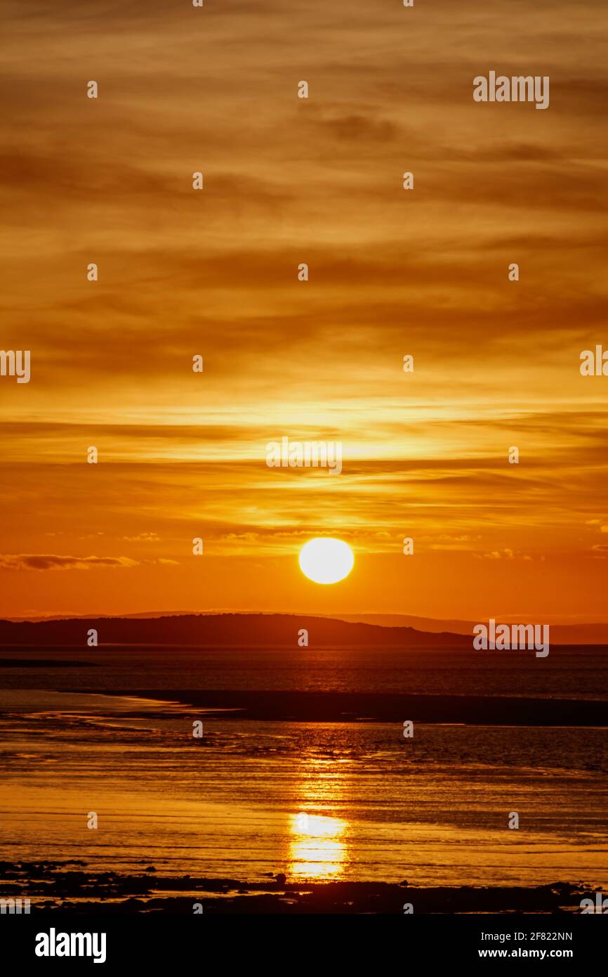 The sun setting over the horizon Stock Photo - Alamy