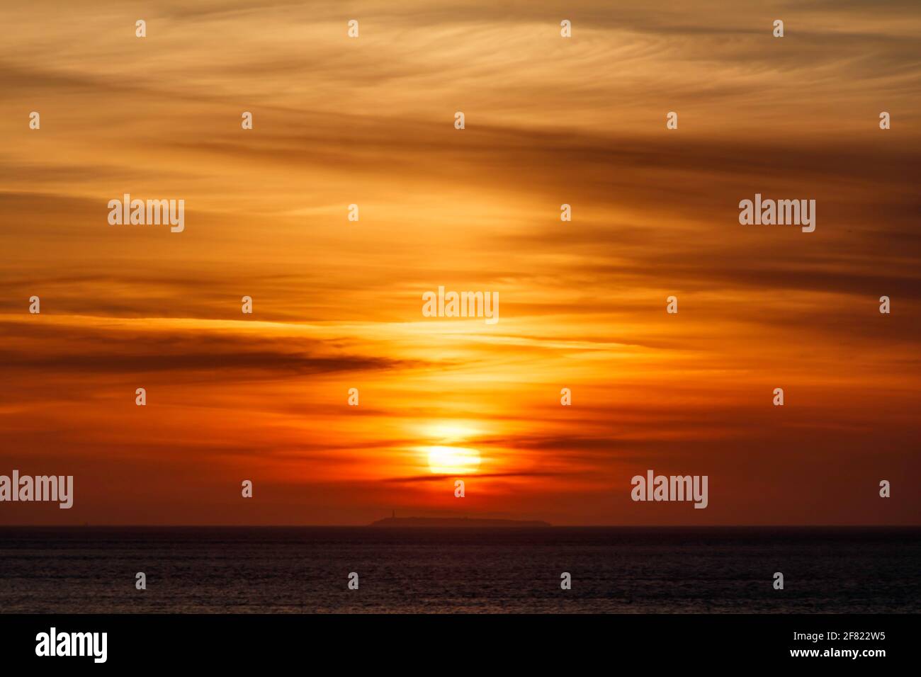 The sun setting over the horizon Stock Photo - Alamy