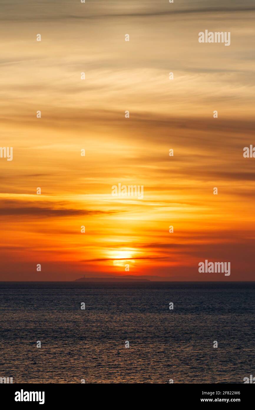 The sun setting over the horizon Stock Photo - Alamy