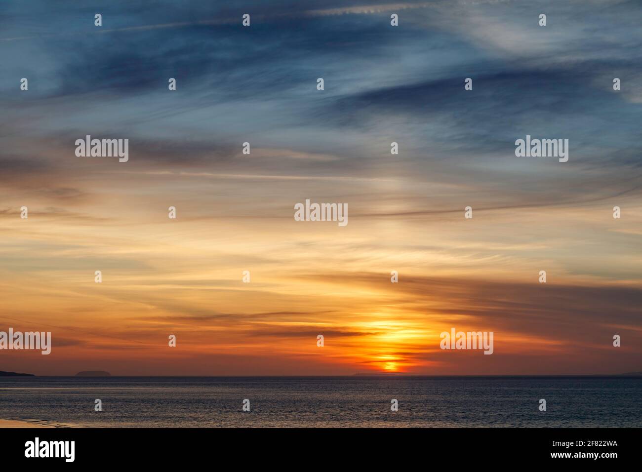 The sun setting over the horizon Stock Photo - Alamy