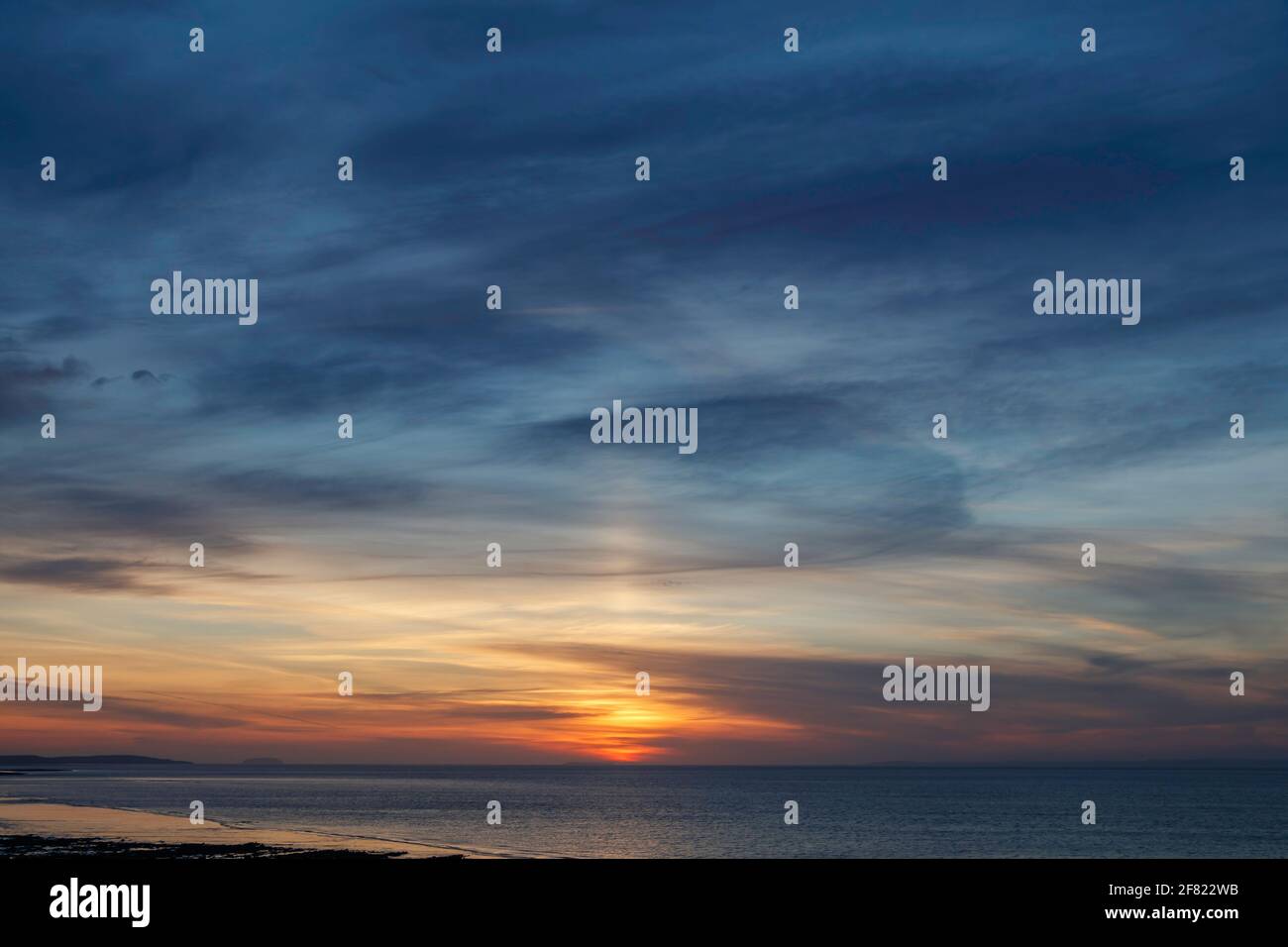 The sun setting over the horizon Stock Photo - Alamy