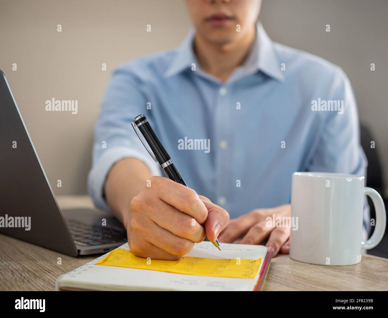 Taking note on notebook close up with computer laptop Stock Photo - Alamy