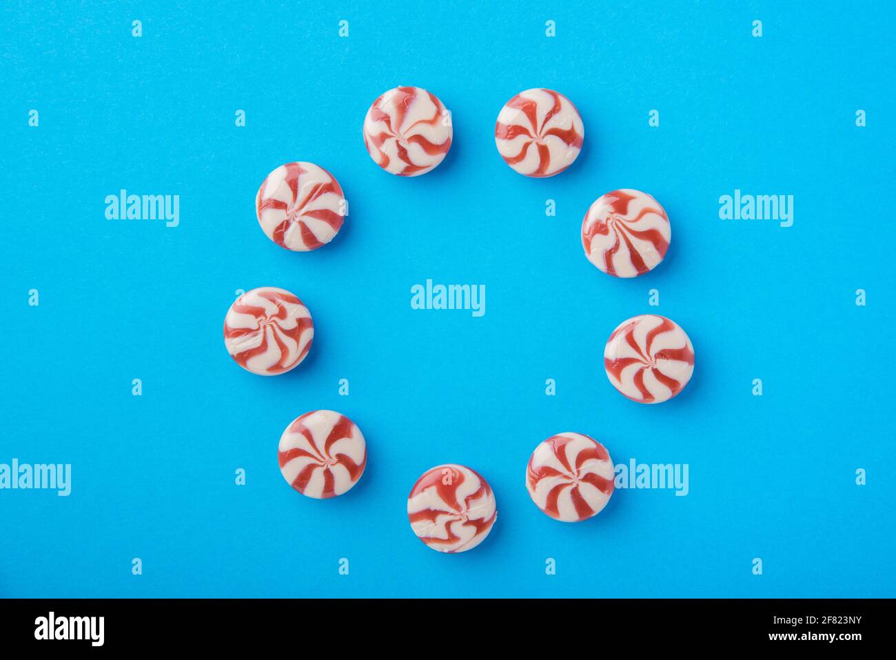Round candy caramel red and white on a blue background Stock Photo - Alamy