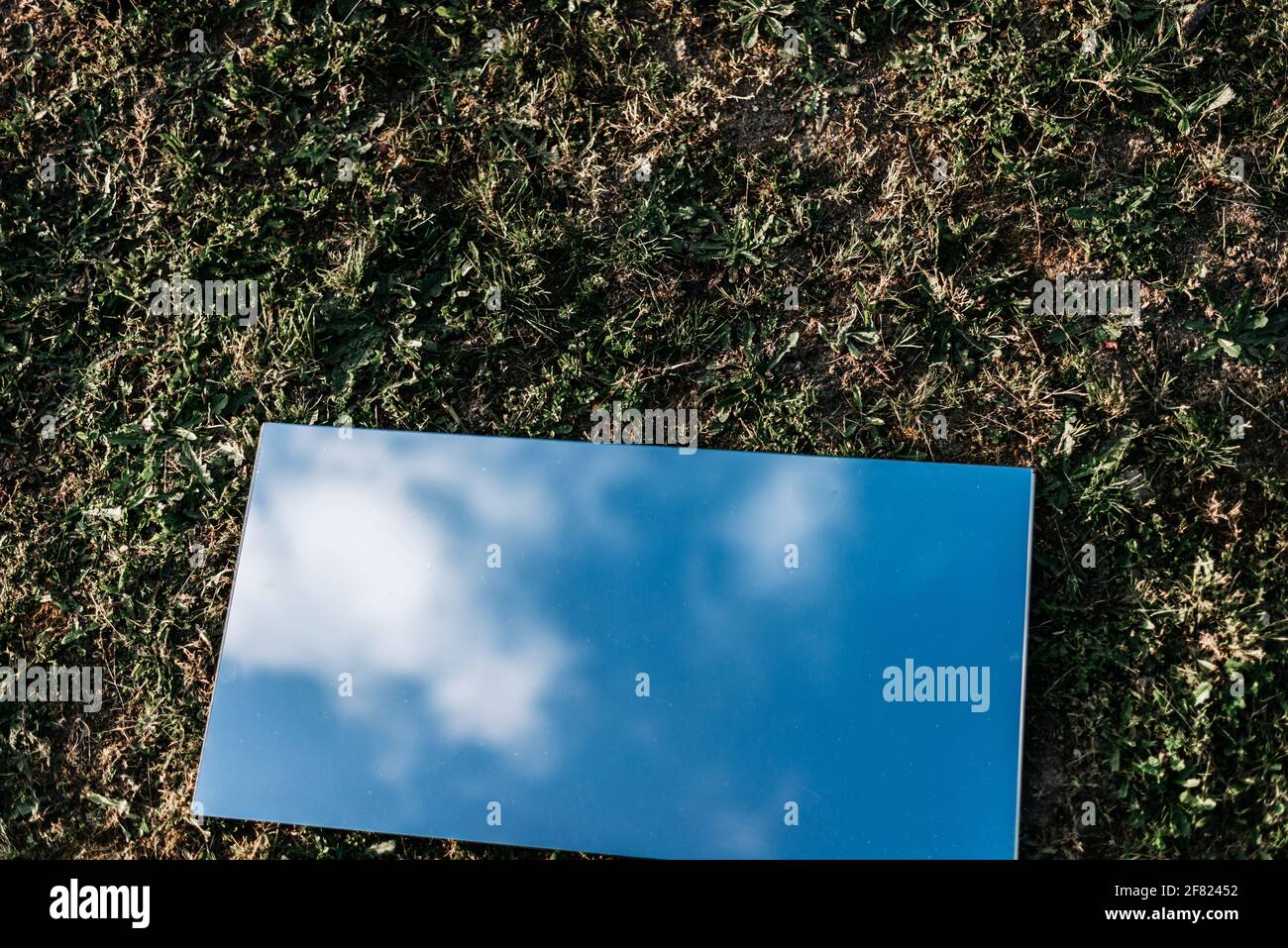 Amazing flat lay of a mirror on the grass, where you can see the clouds ...