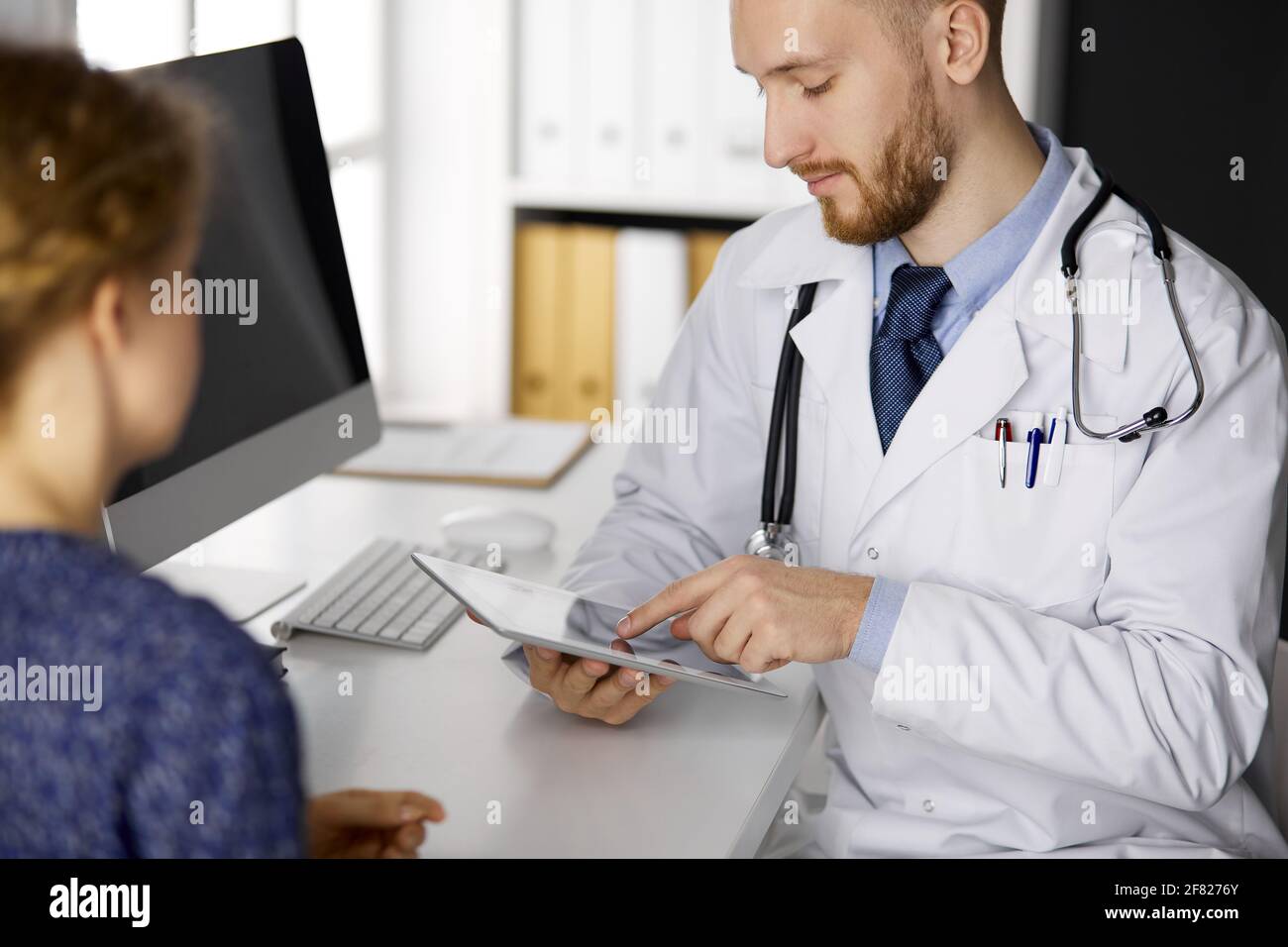 Friendly red-bearded doctor and patient woman discussing current health ...