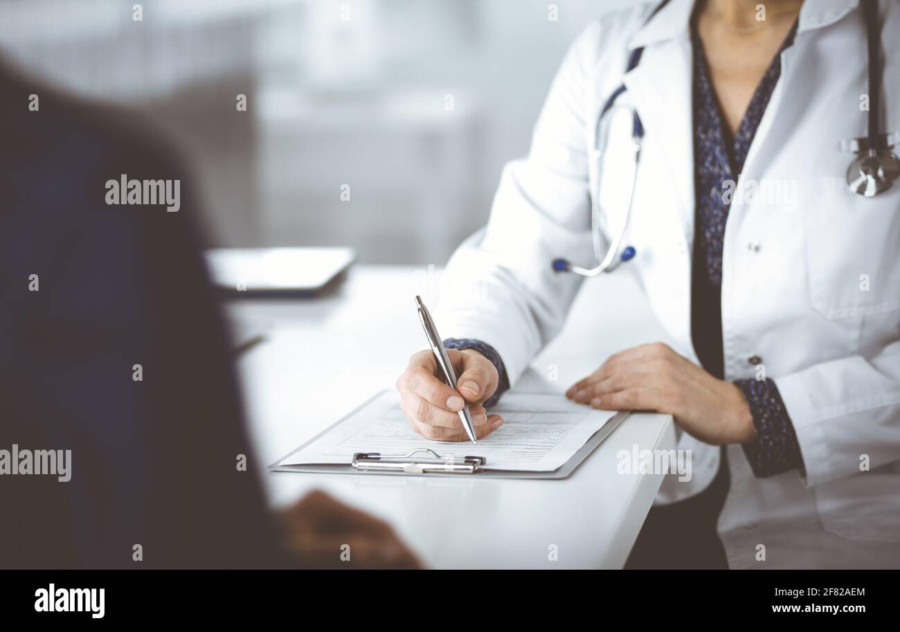 Unknown woman-doctor is writing some medical recommendations to her ...