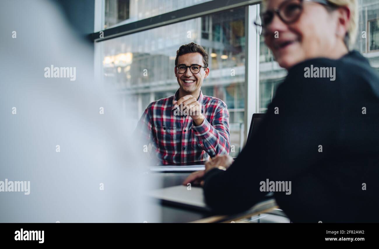 Happy young businessman in team meeting. Male professional smiling ...