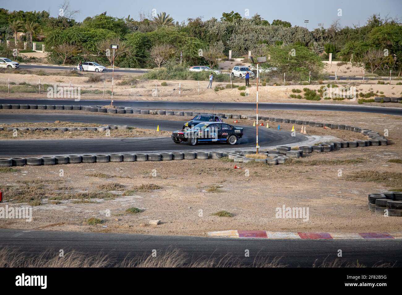 cars on tarmac tack drag racing with smoke in desert during day time ...