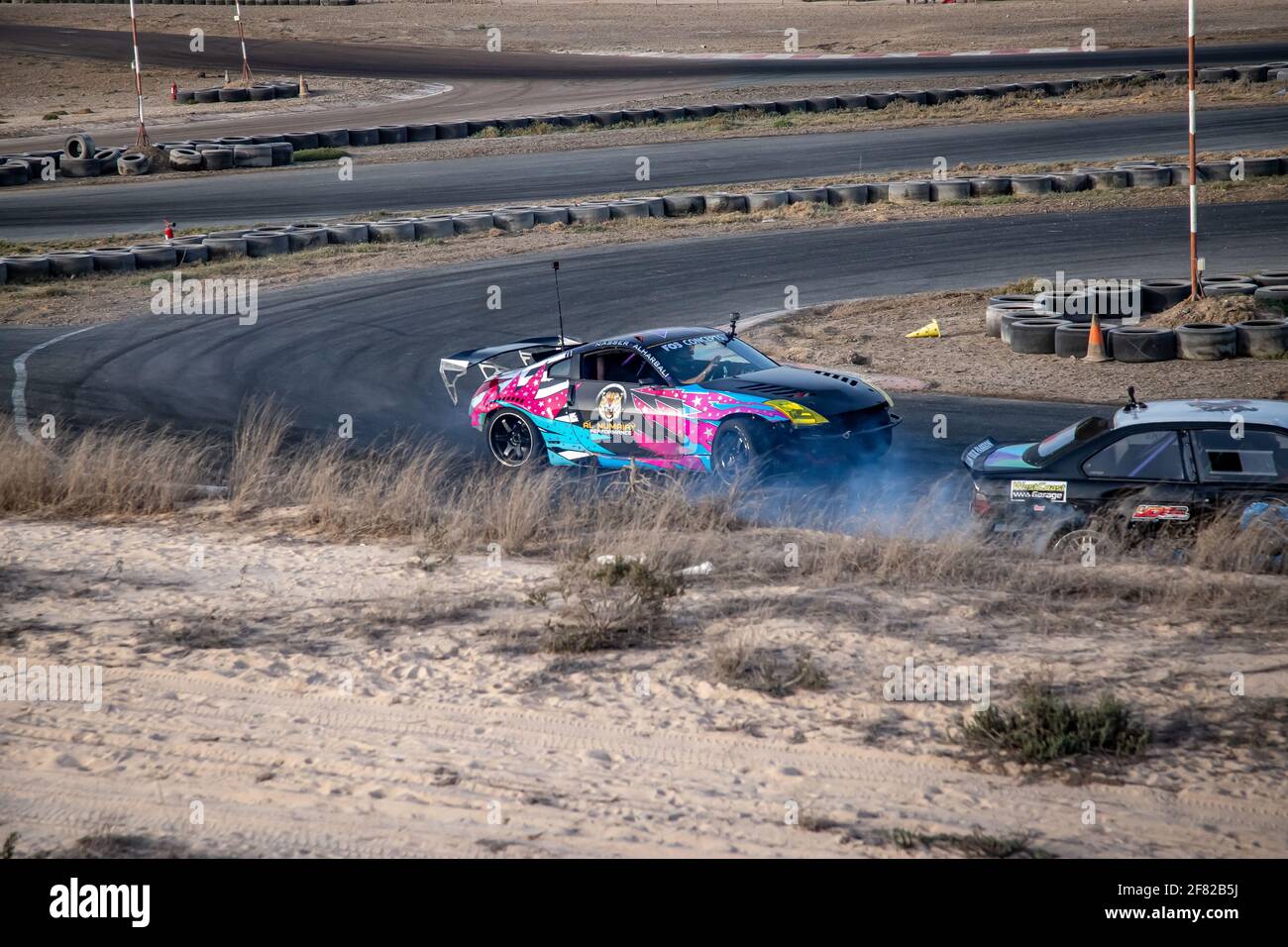 cars on tarmac tack drag racing with smoke in desert during day time ...