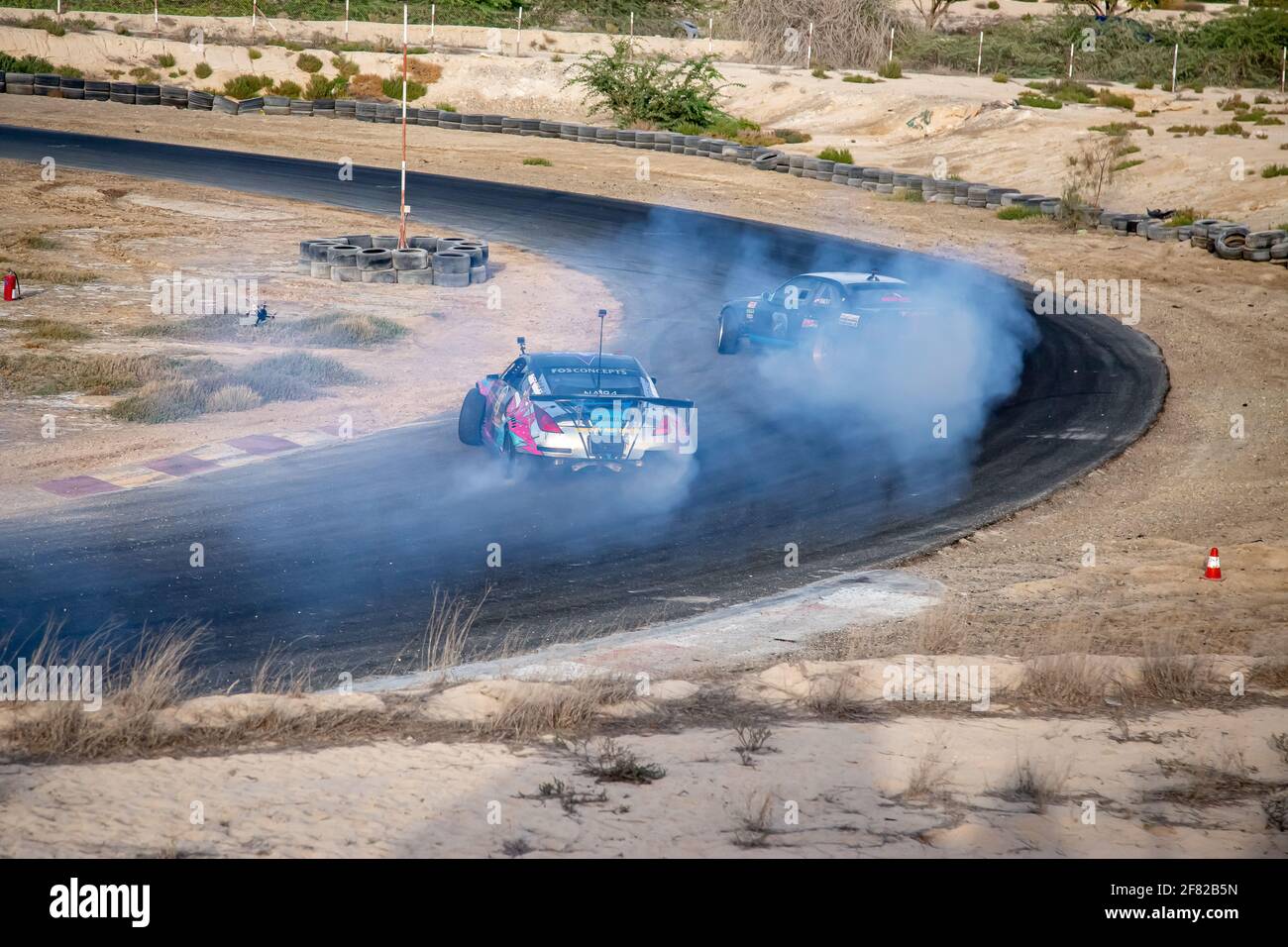 cars on tarmac tack drag racing with smoke in desert during day time ...