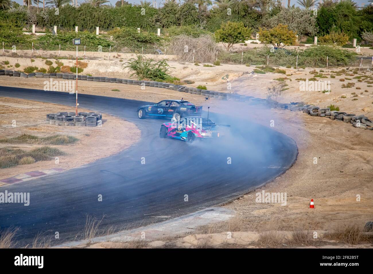 cars on tarmac tack drag racing with smoke in desert during day time ...