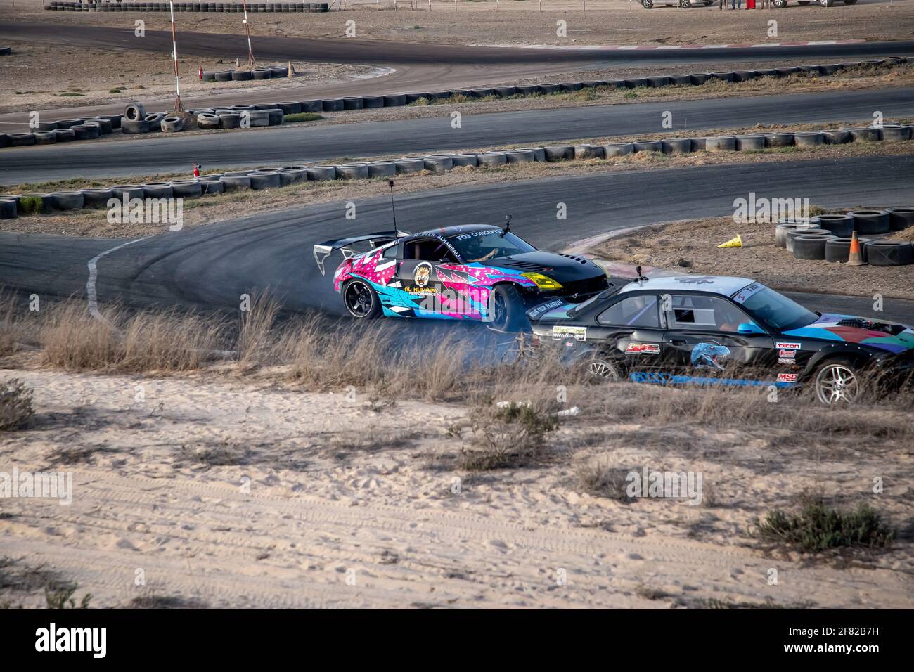 cars on tarmac tack drag racing with smoke in desert during day time ...