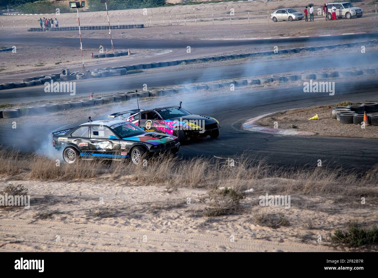 cars on tarmac tack drag racing with smoke in desert during day time ...