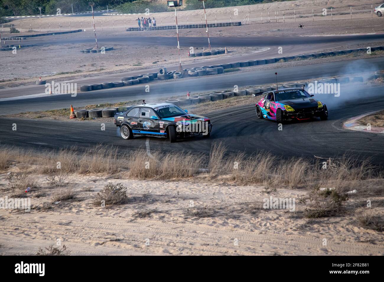 cars on tarmac tack drag racing with smoke in desert during day time ...