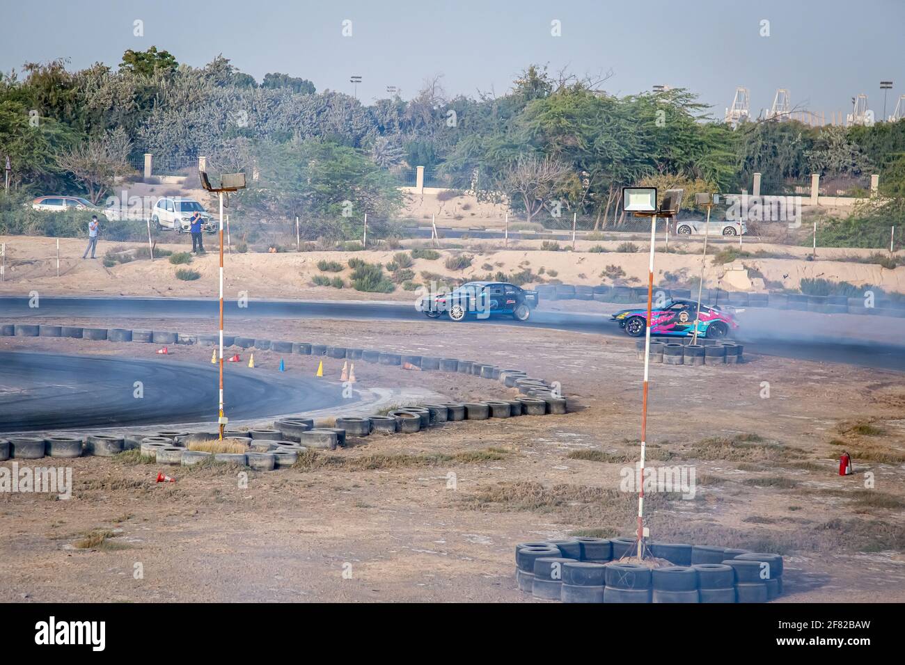 cars on tarmac tack drag racing with smoke in desert during day time ...