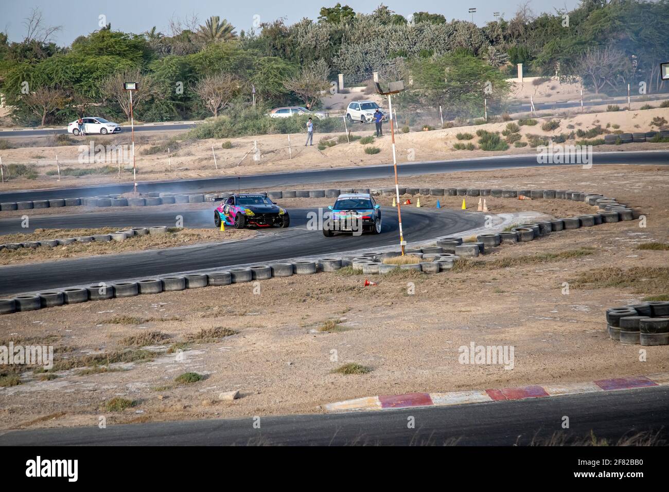cars on tarmac tack drag racing with smoke in desert during day time ...