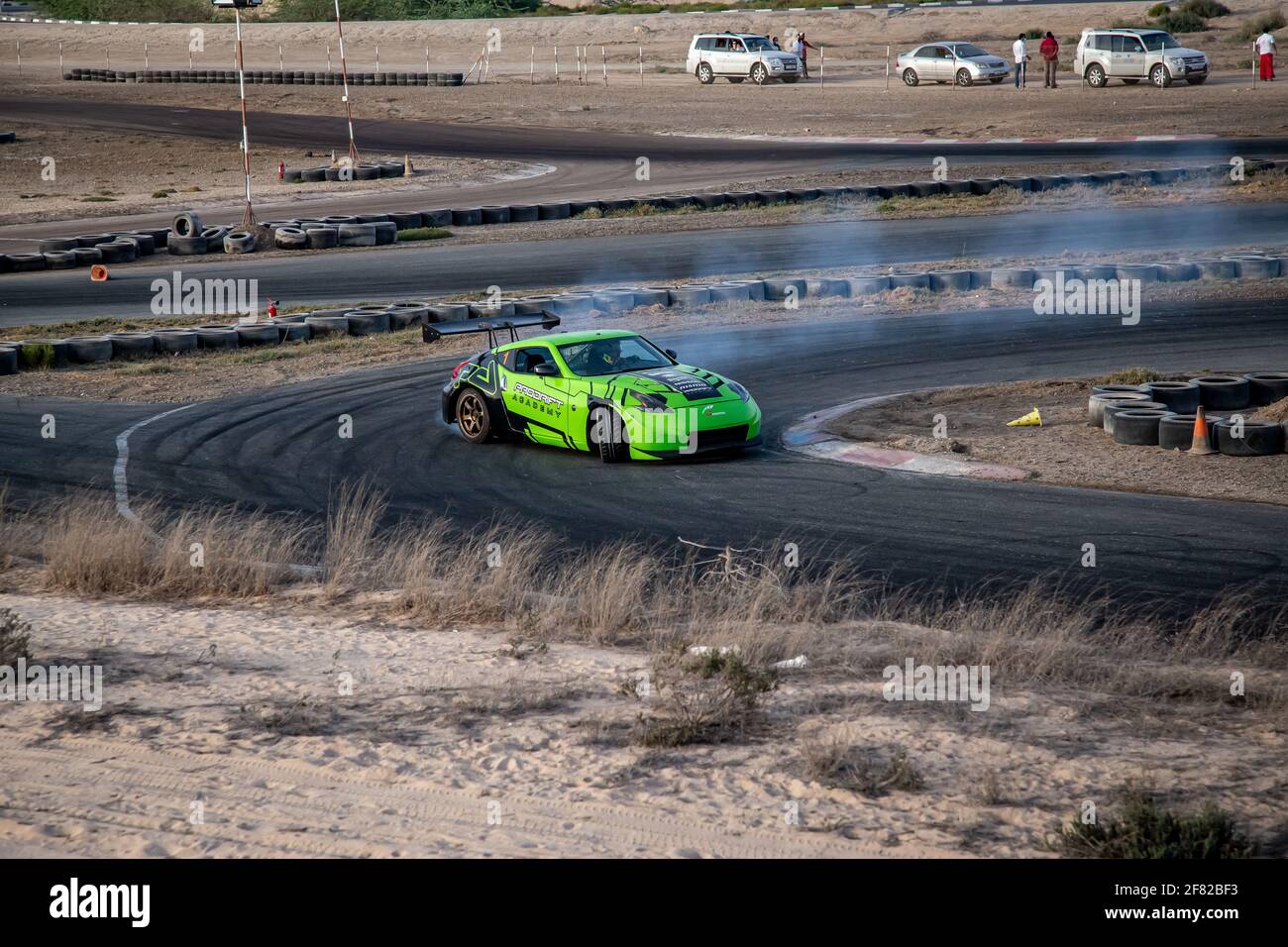 cars on tarmac tack drag racing with smoke in desert during day time ...
