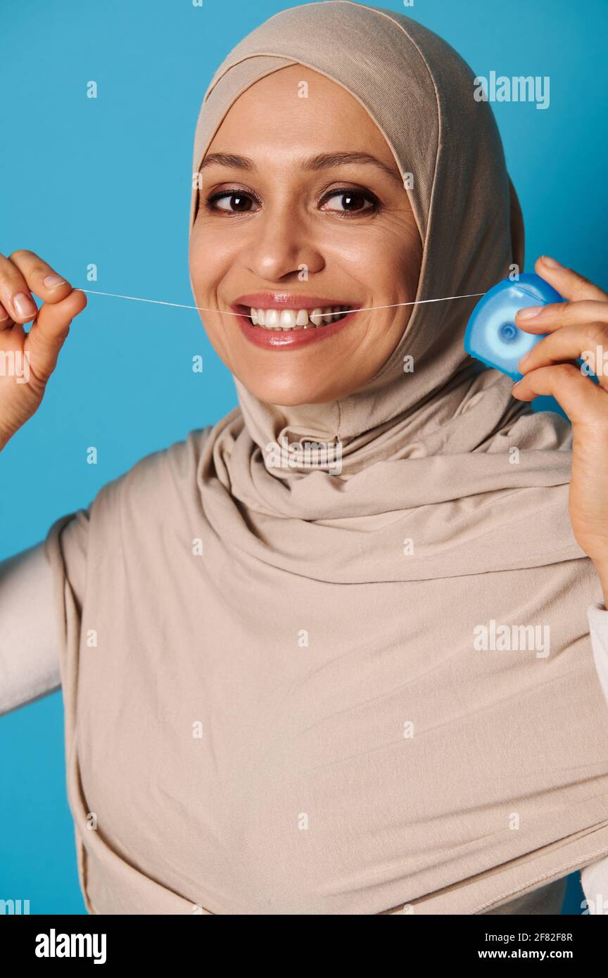 Young Muslim woman with beautiful and healthy smile flossing teeth on ...