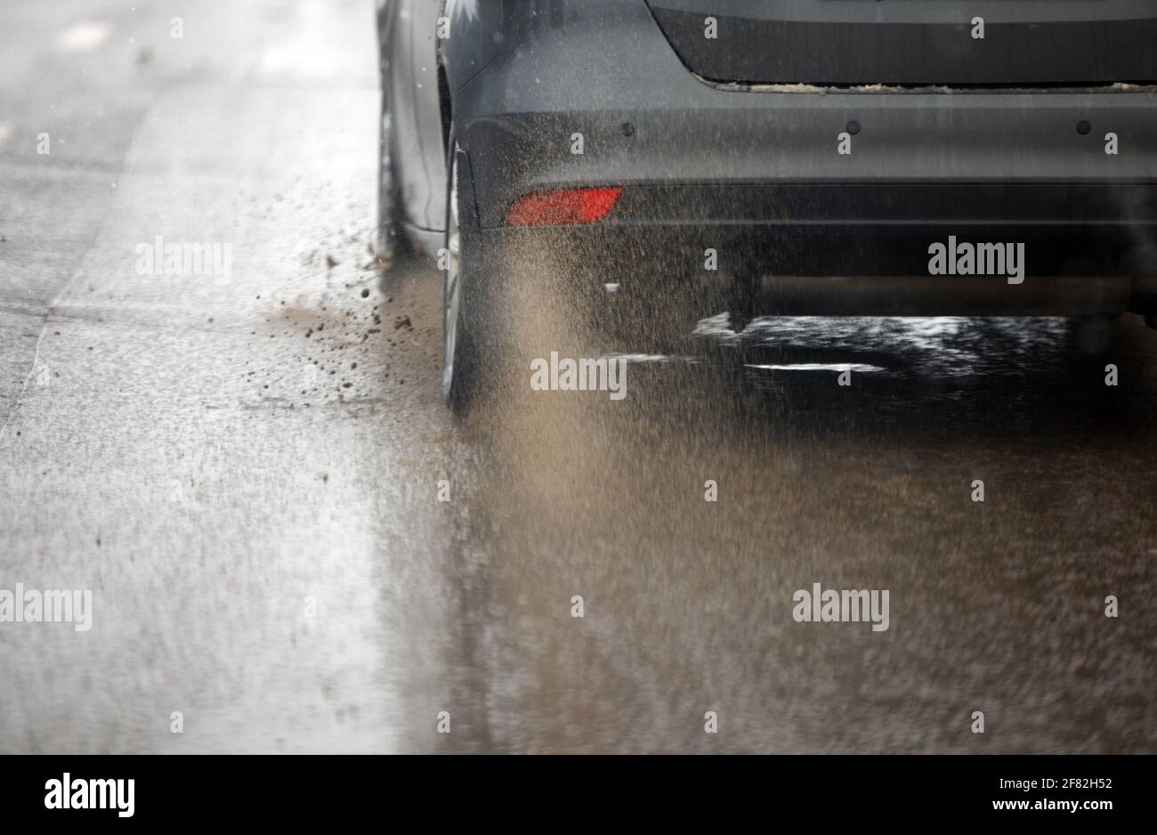 Dirt water splash flow from wheels of silver car moving fast in ...